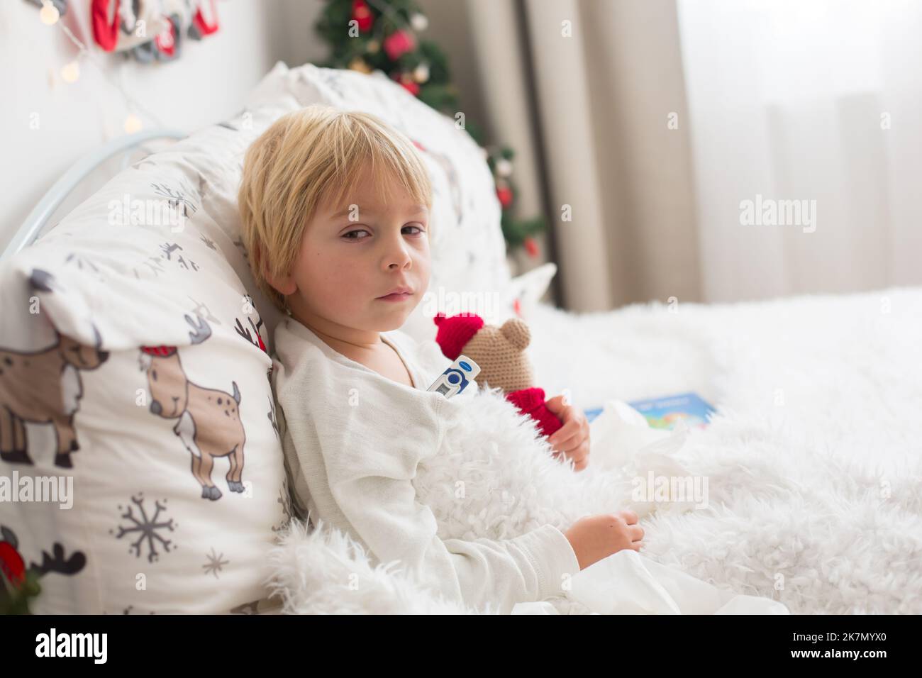 Beautiful blond toddler child, sick boy with fever, lying in bed on ...