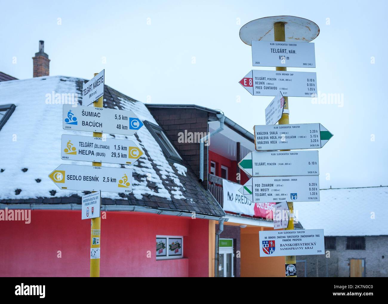 Trail signs in Telgart, Slovakia with a red snowy building in the ...