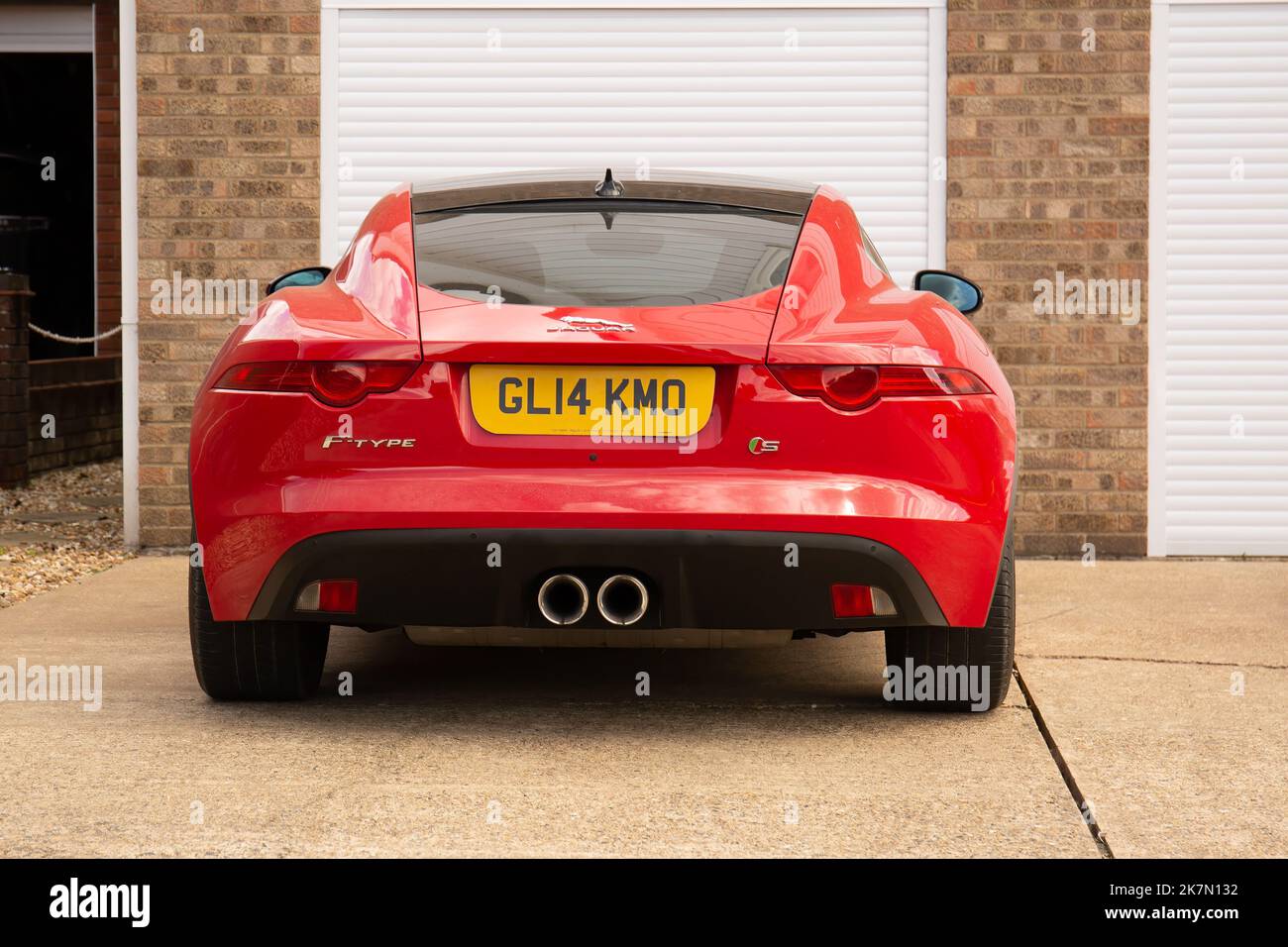 The backside of a red F-type Jaguar luxury car parked in front of a ...