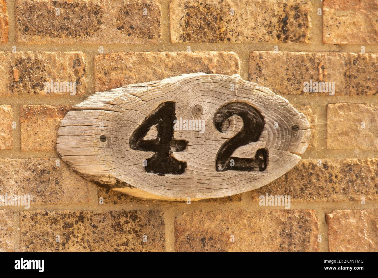 Number 42 painted in black on a weathered oval plaque on the brick wall ...