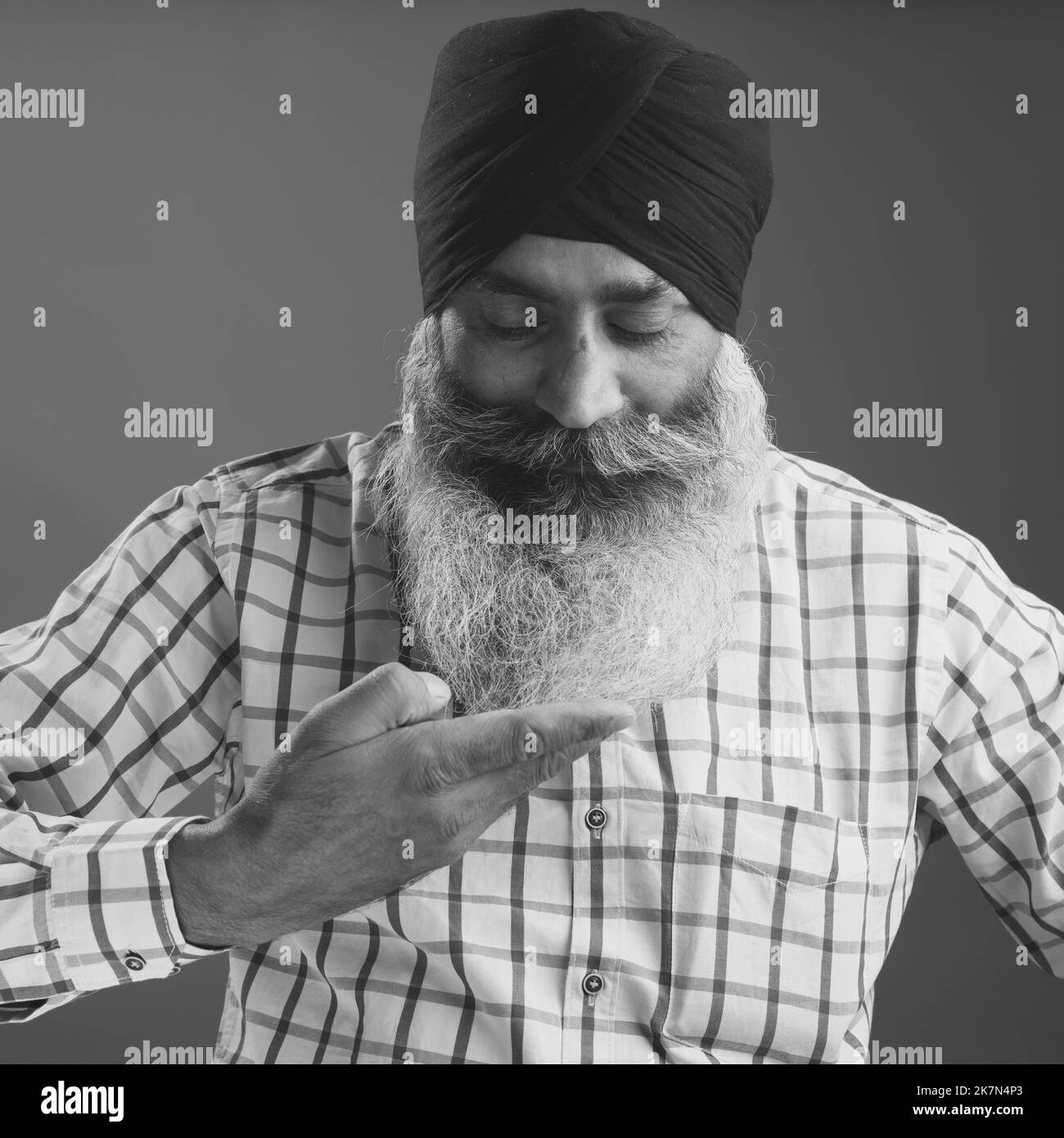 A grayscale shot of an Indian male wearing a turban looking down and ...