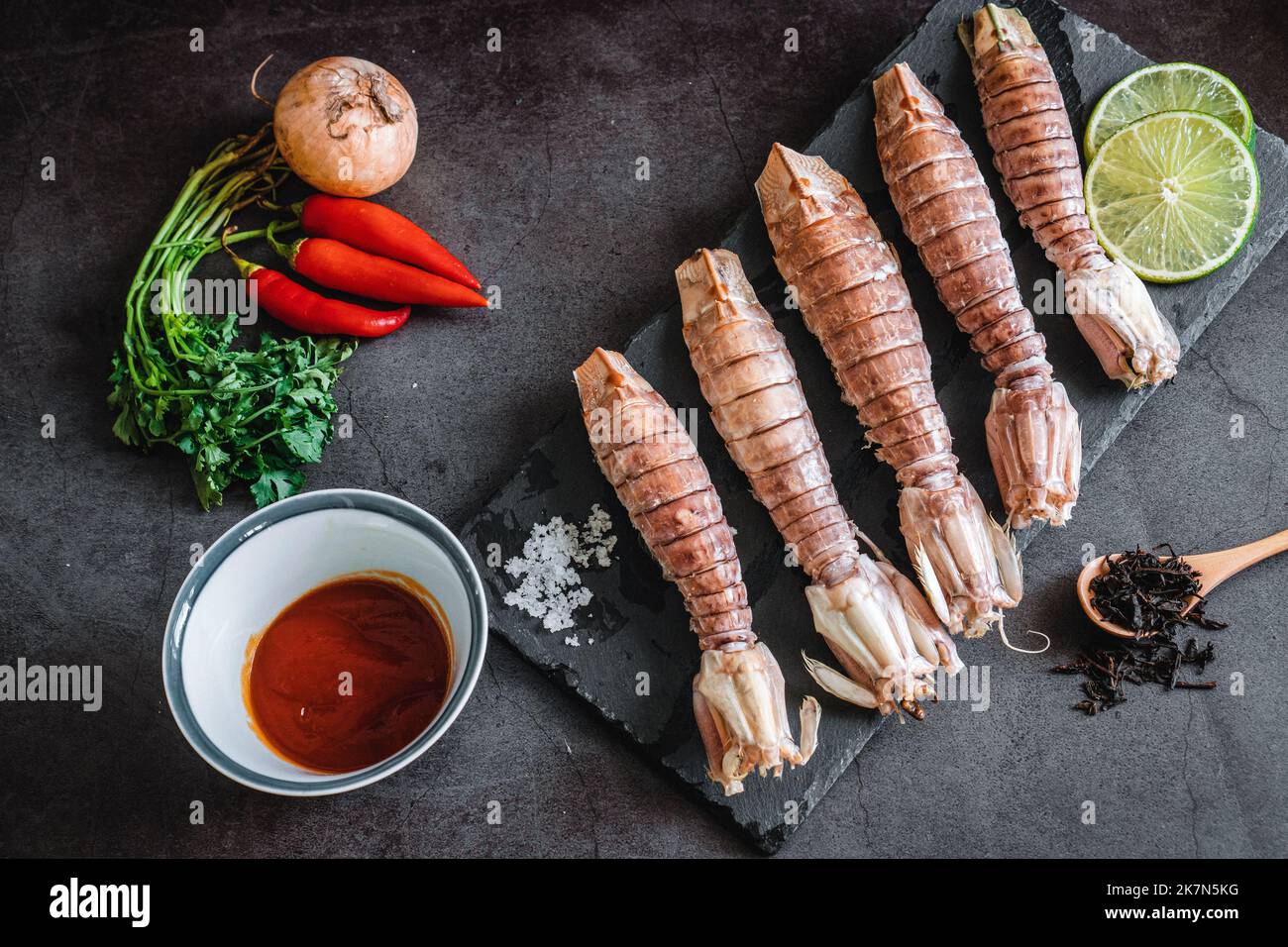 A top view of raw mantis shrimp, lime slices, garlic, peppers, and ...