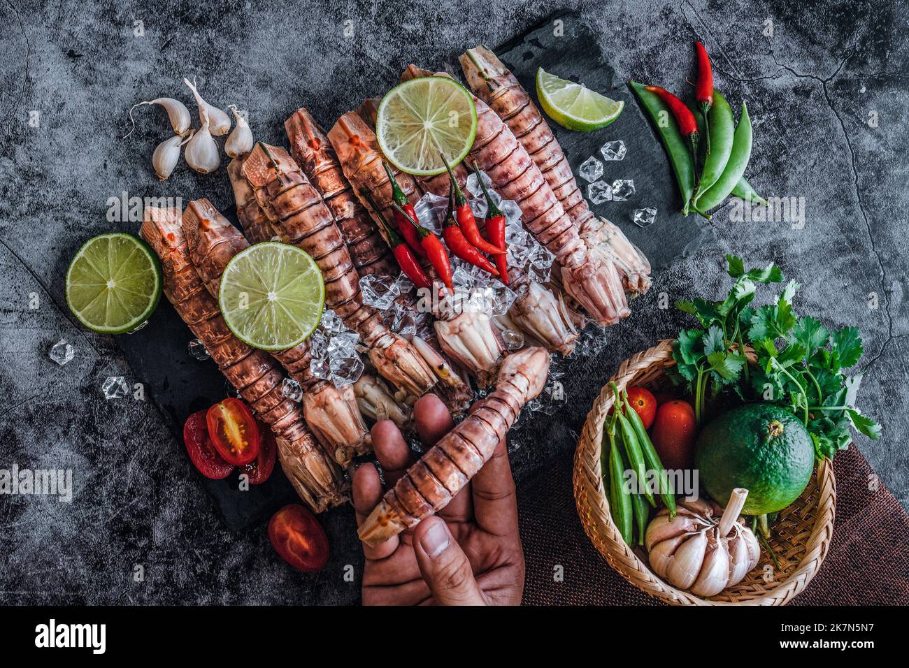 A top view of raw mantis shrimp, lime slices, garlic, and peppers on a ...