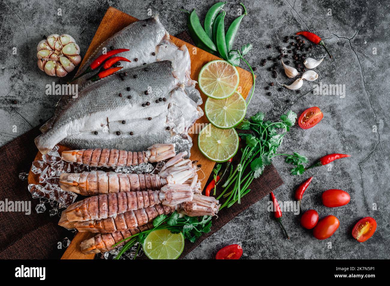 A top view of raw fresh fish and mantis shrimp, lime, garlic, peppers ...