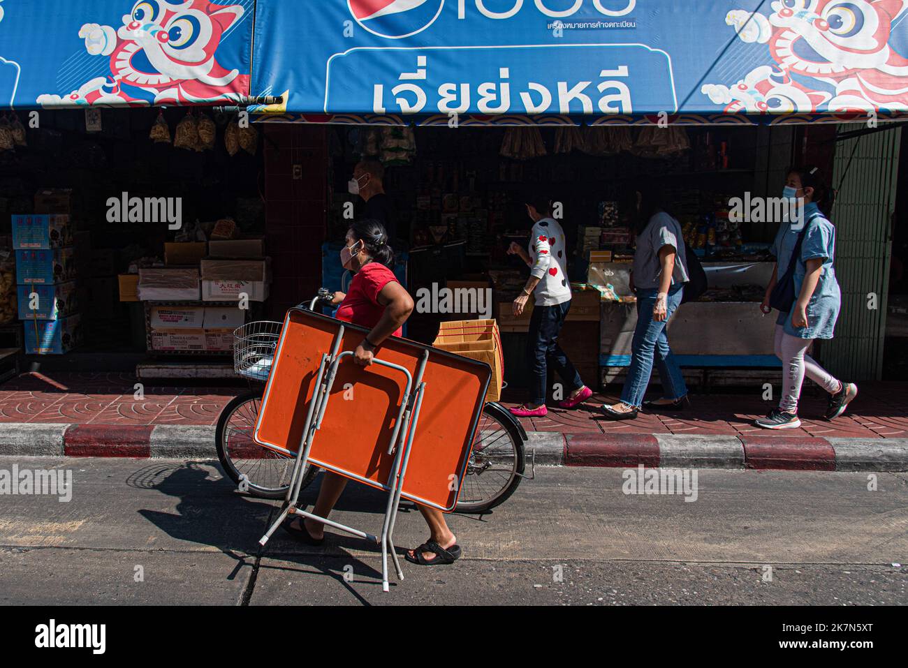 A woman seen carrying a table as she walks along the Yaowarat road ...