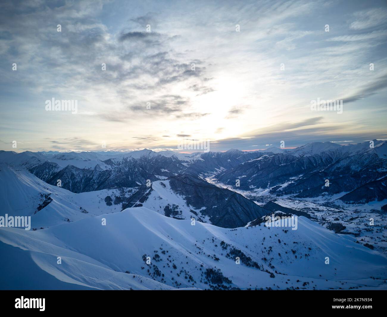 Wide aerial panorama of snowy mountain ridge at ski resort village on ...