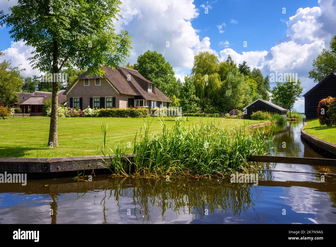 Traditional dutch brick houses with lush green lawns on a water canal ...