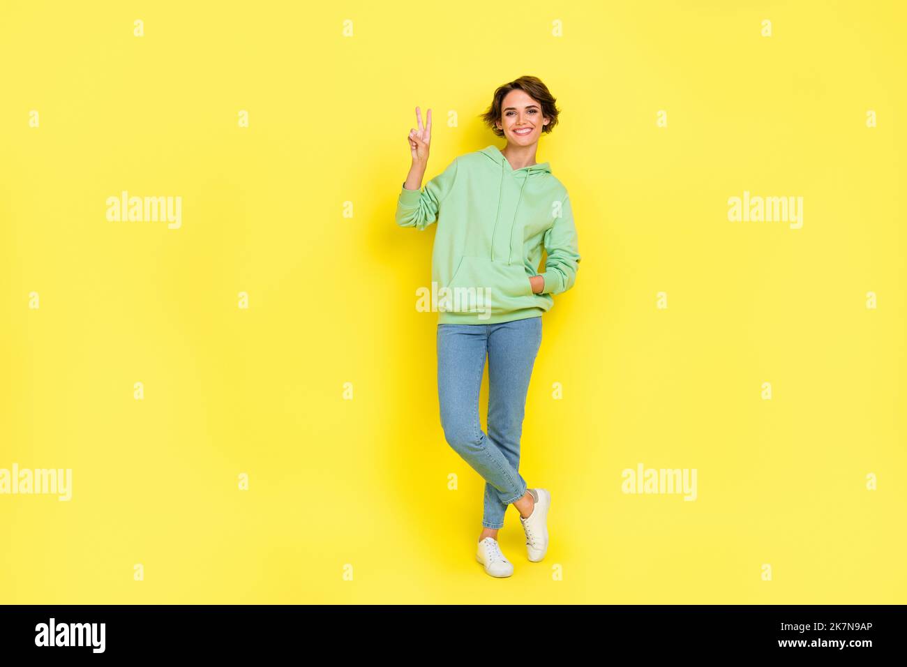 Full length photo of cool pretty lady wear green hoodie showing v-sign ...