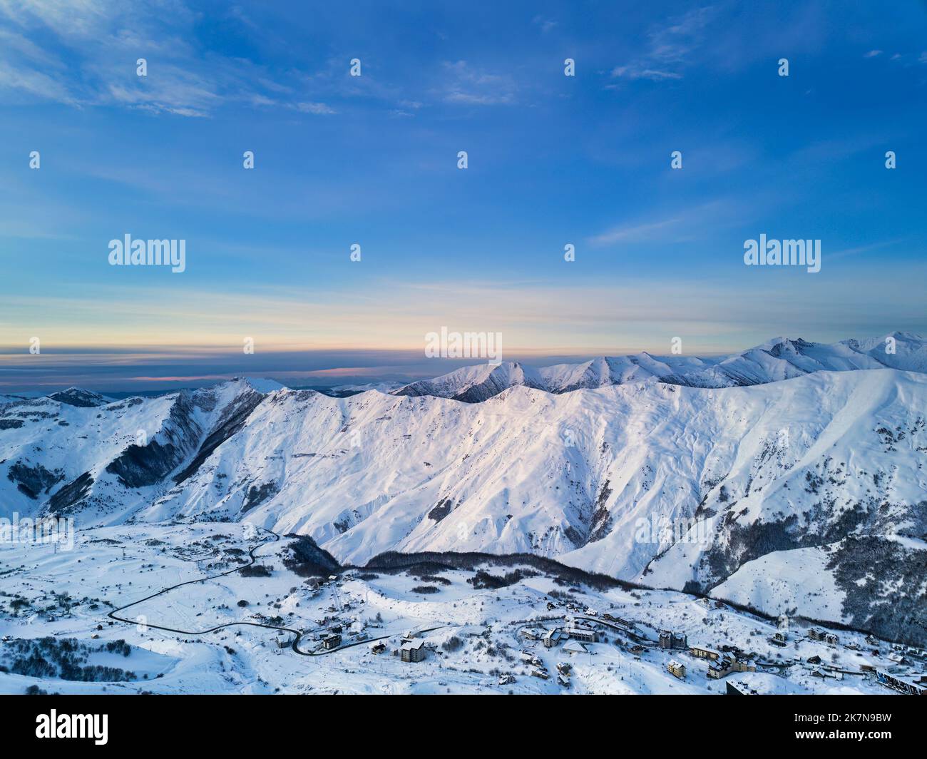 Wide aerial panorama of snowy mountain ridge at ski resort village on ...