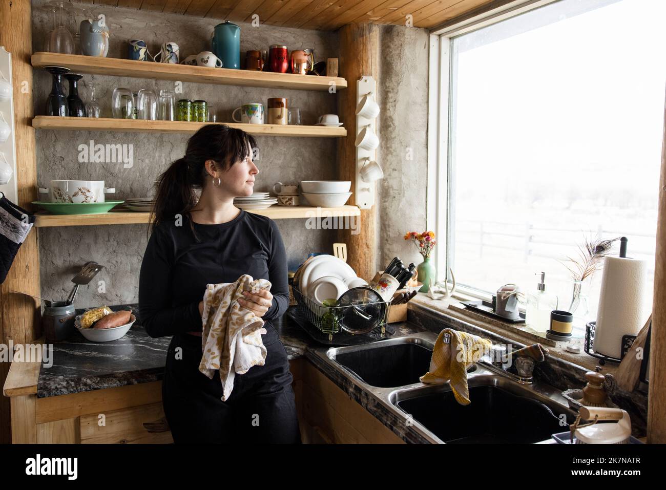 Woman looking out of window in cabin kitchen Stock Photo - Alamy