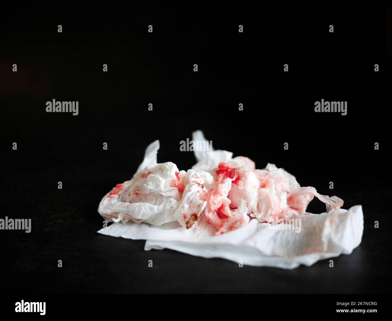 Fresh red blood stained on tissue paper isolated on dark background ...