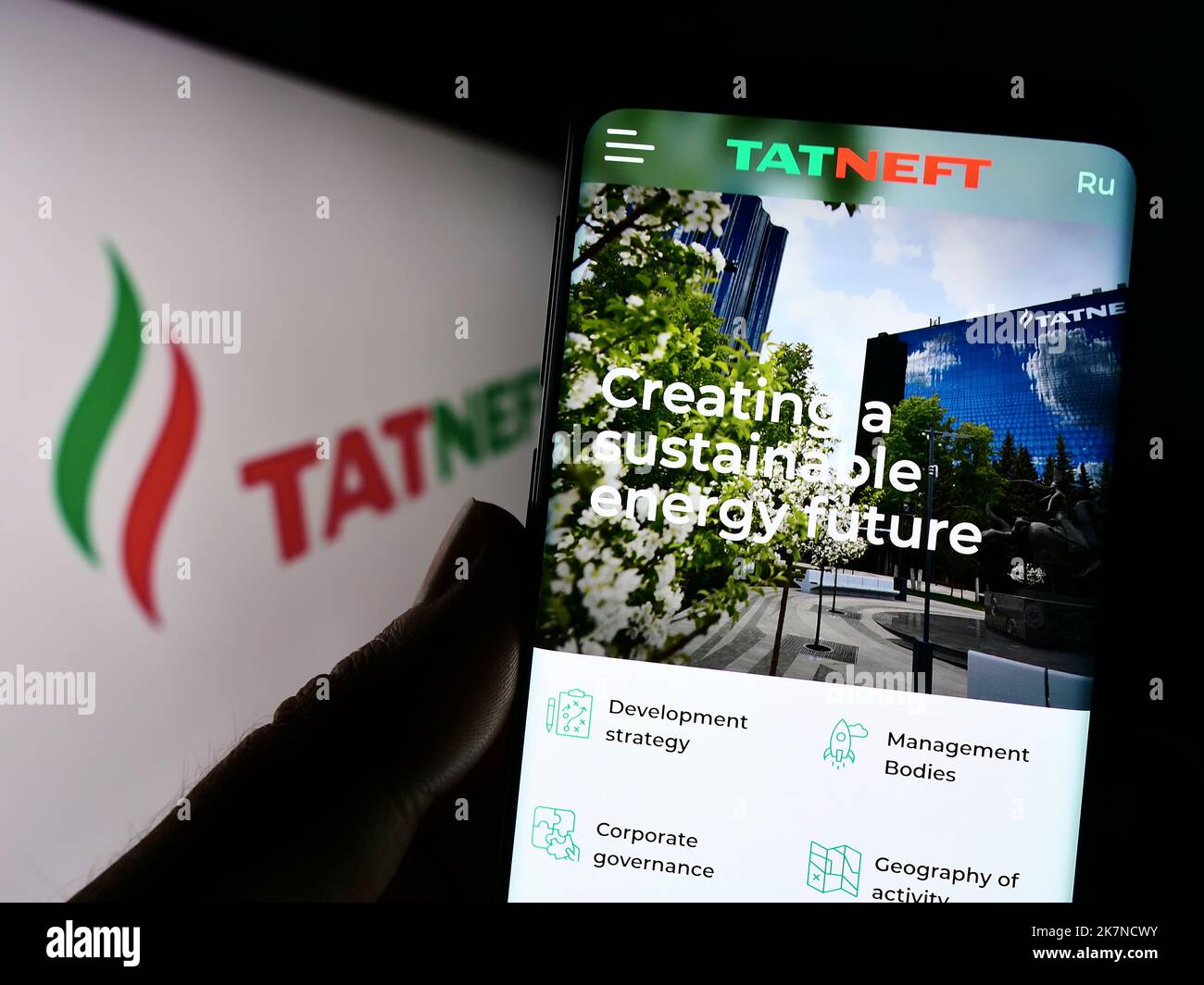 Person holding smartphone with website of Russian oil and gas company Tatneft on screen in front ...