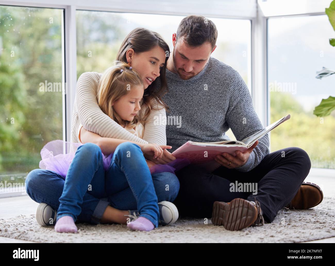 Expand your mind with some knowledge. a young family reading a book at ...