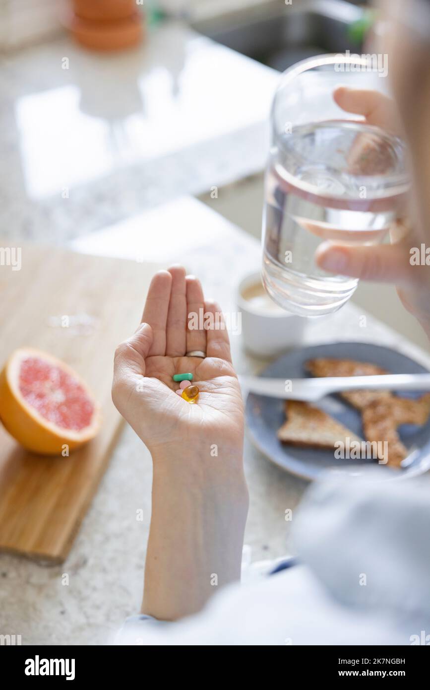 Woman taking medication with breakfast Stock Photo - Alamy