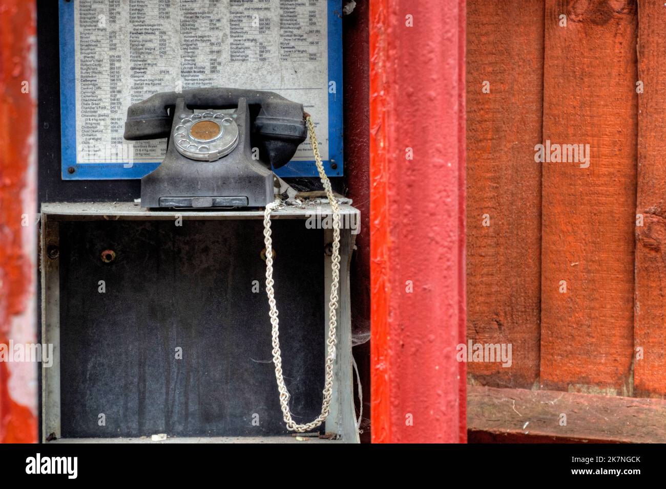 Black vintage old fashioned telephone with dial in red telephone box ...
