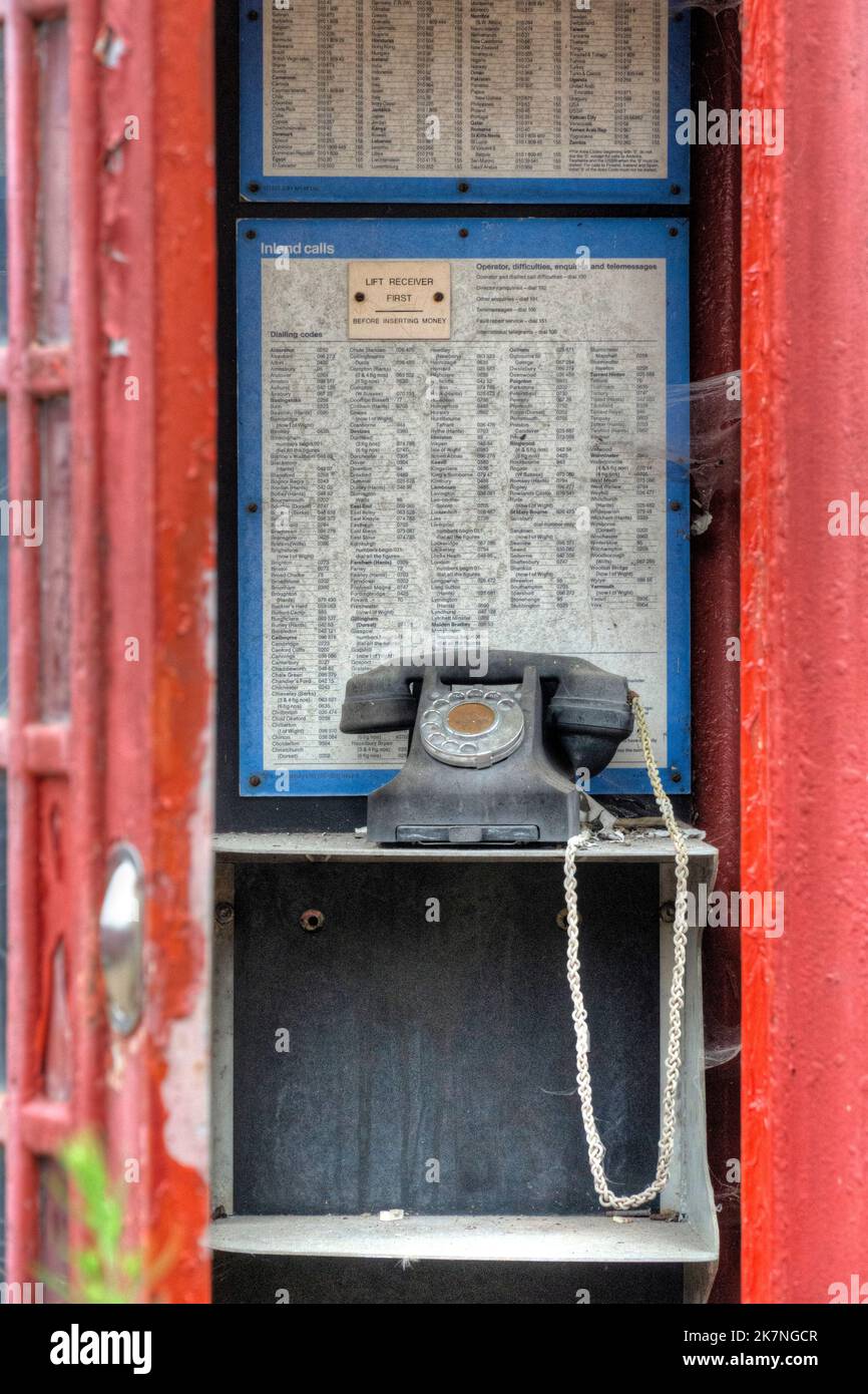 Black vintage old fashioned telephone with dial in red telephone box ...