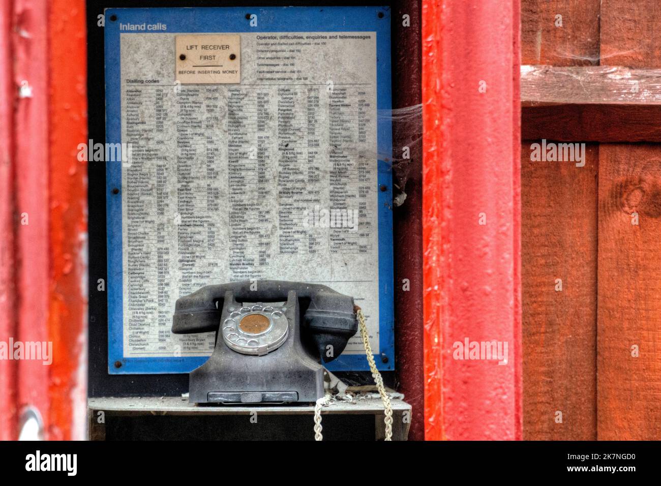 Black vintage old fashioned telephone with dial in red telephone box ...