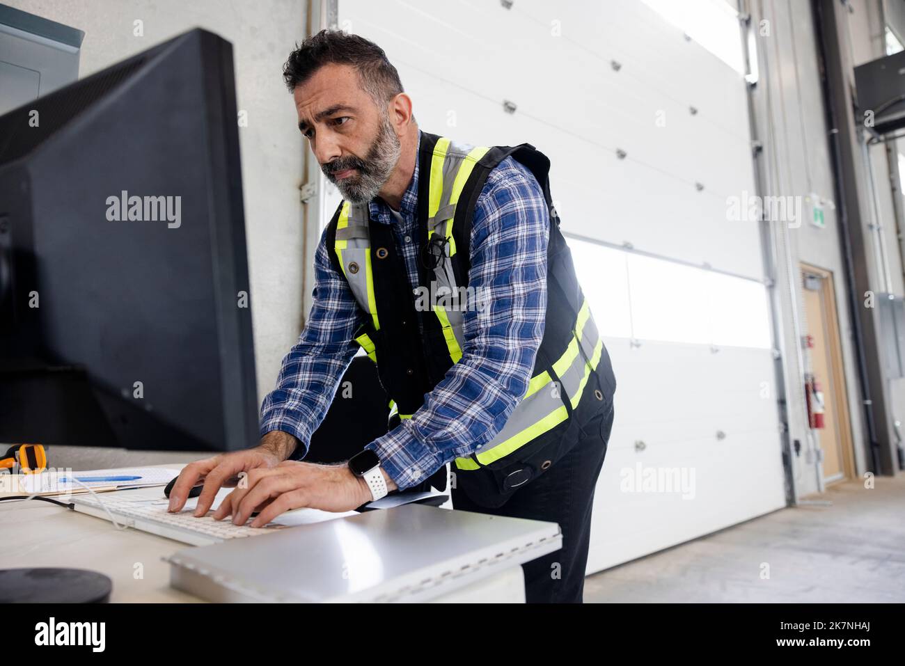 Construction supervisor working on computer on desk in warehouse Stock ...