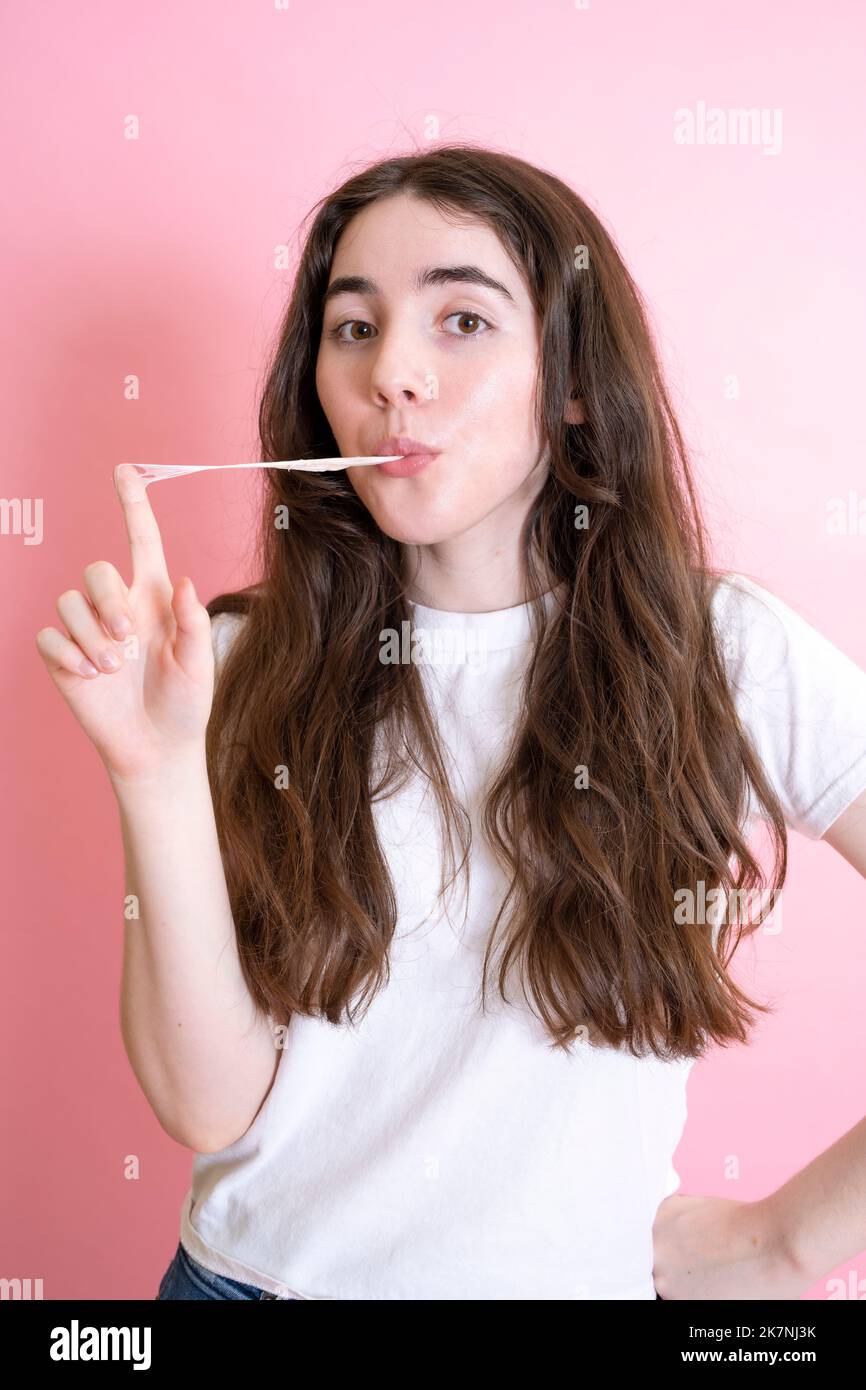 Portrait of a Young Woman Blowing Bubble Gum Bubbles Against a Pink ...