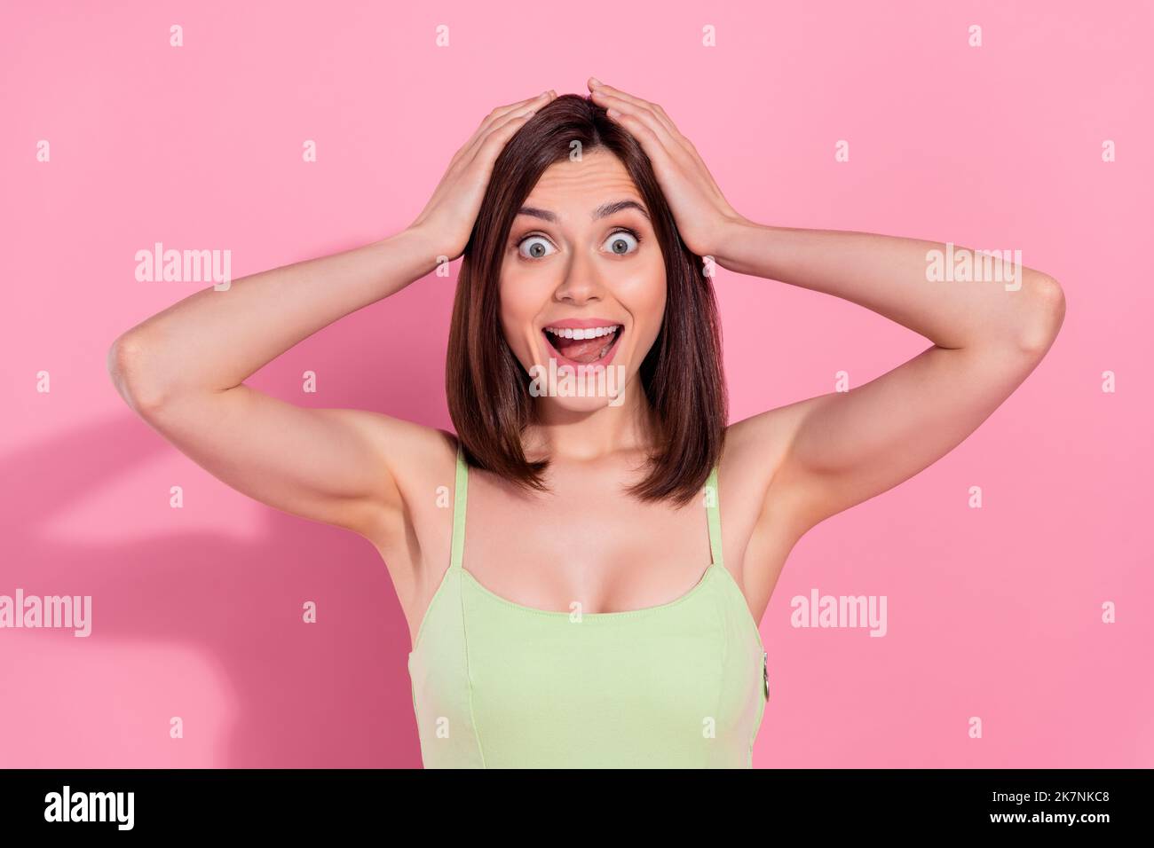 Photo of sweet impressed young girl dressed green outfit arms head open ...