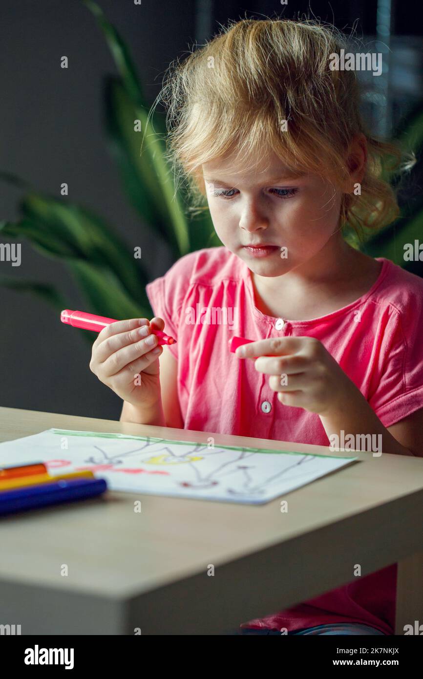 Child drawing a picture of her family with colored markers. Little girl ...