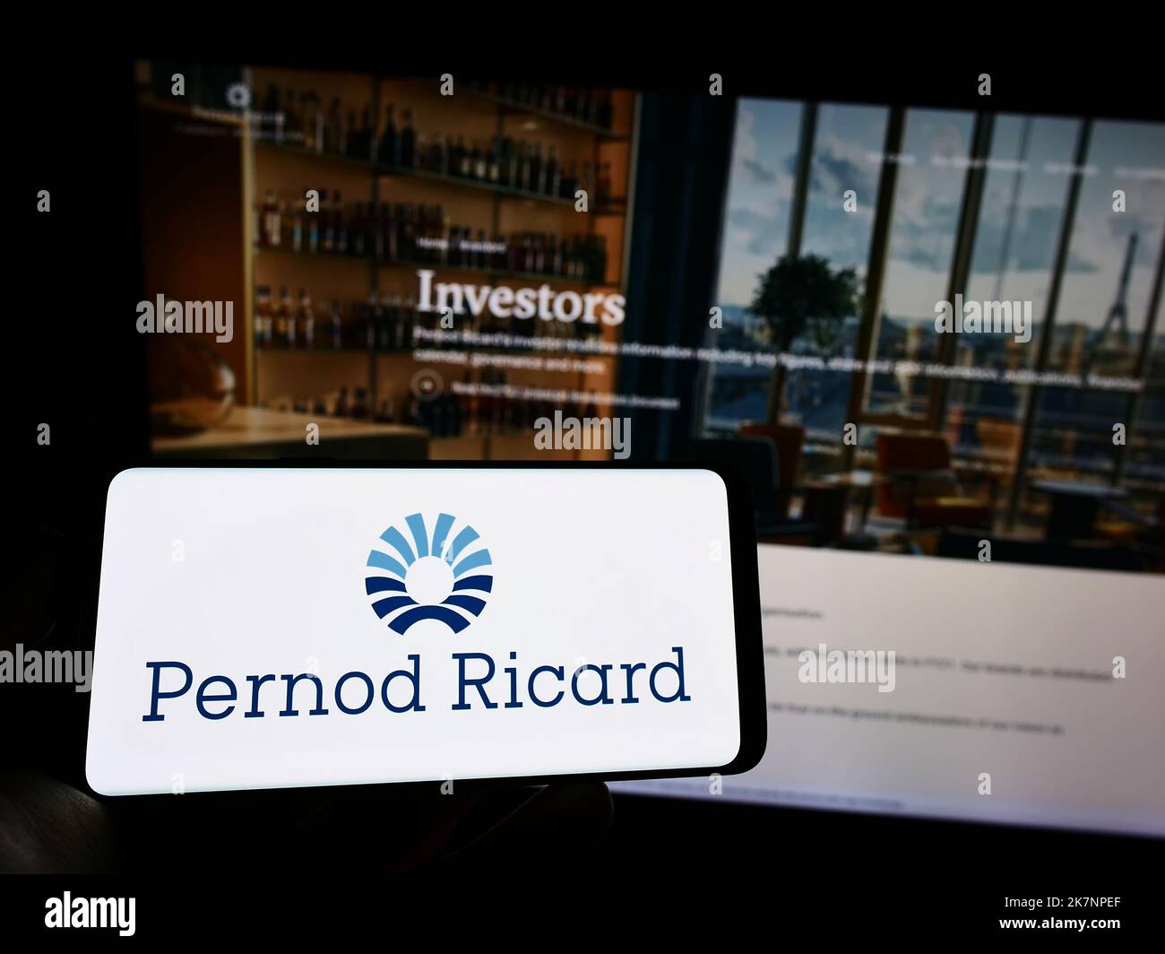 Person holding mobile phone with logo of French beverage company Pernod ...