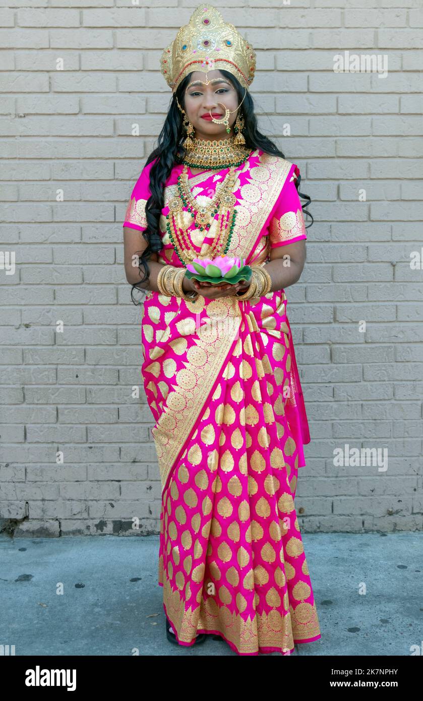 An attractive Hindu woman dressed as Lakshmi, wearing a crown & holding ...