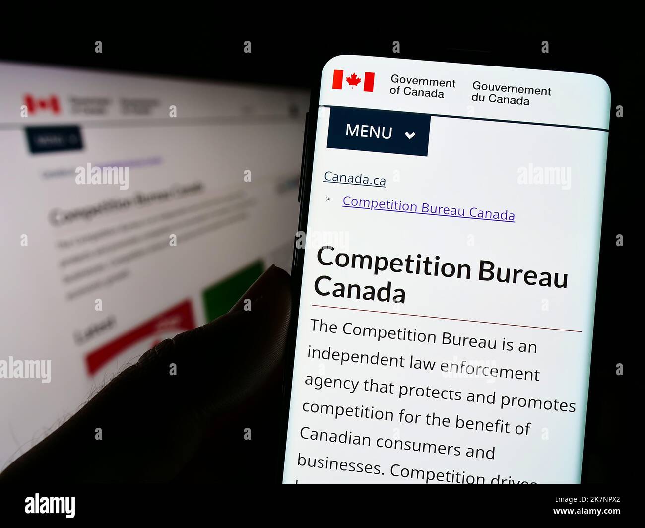 Person holding cellphone with website and logo of Canadian regulator ...