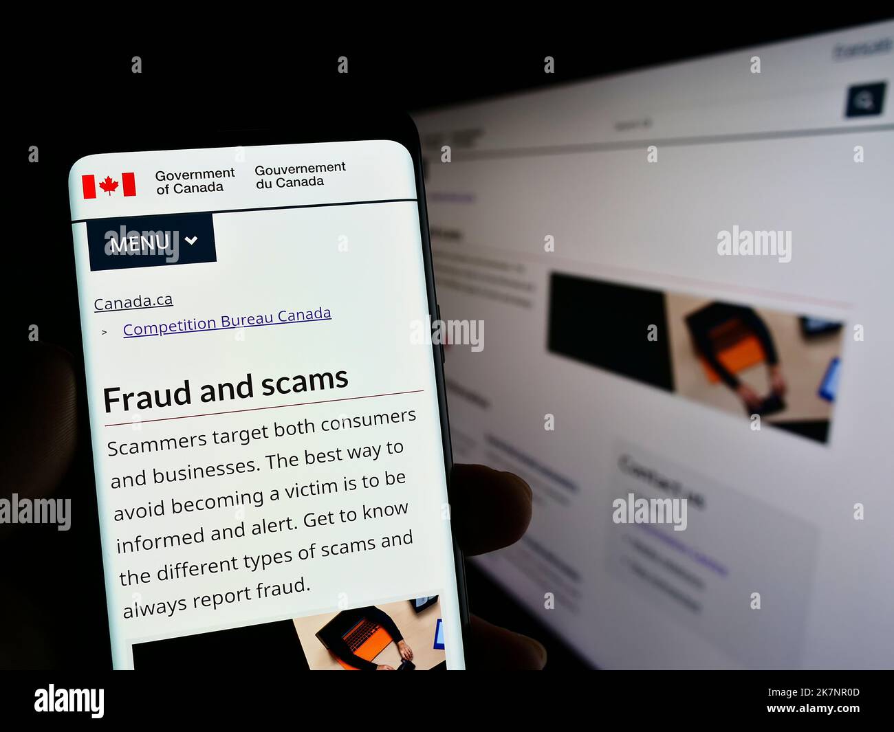 Person holding smartphone with webpage and logo of Canadian regulator ...