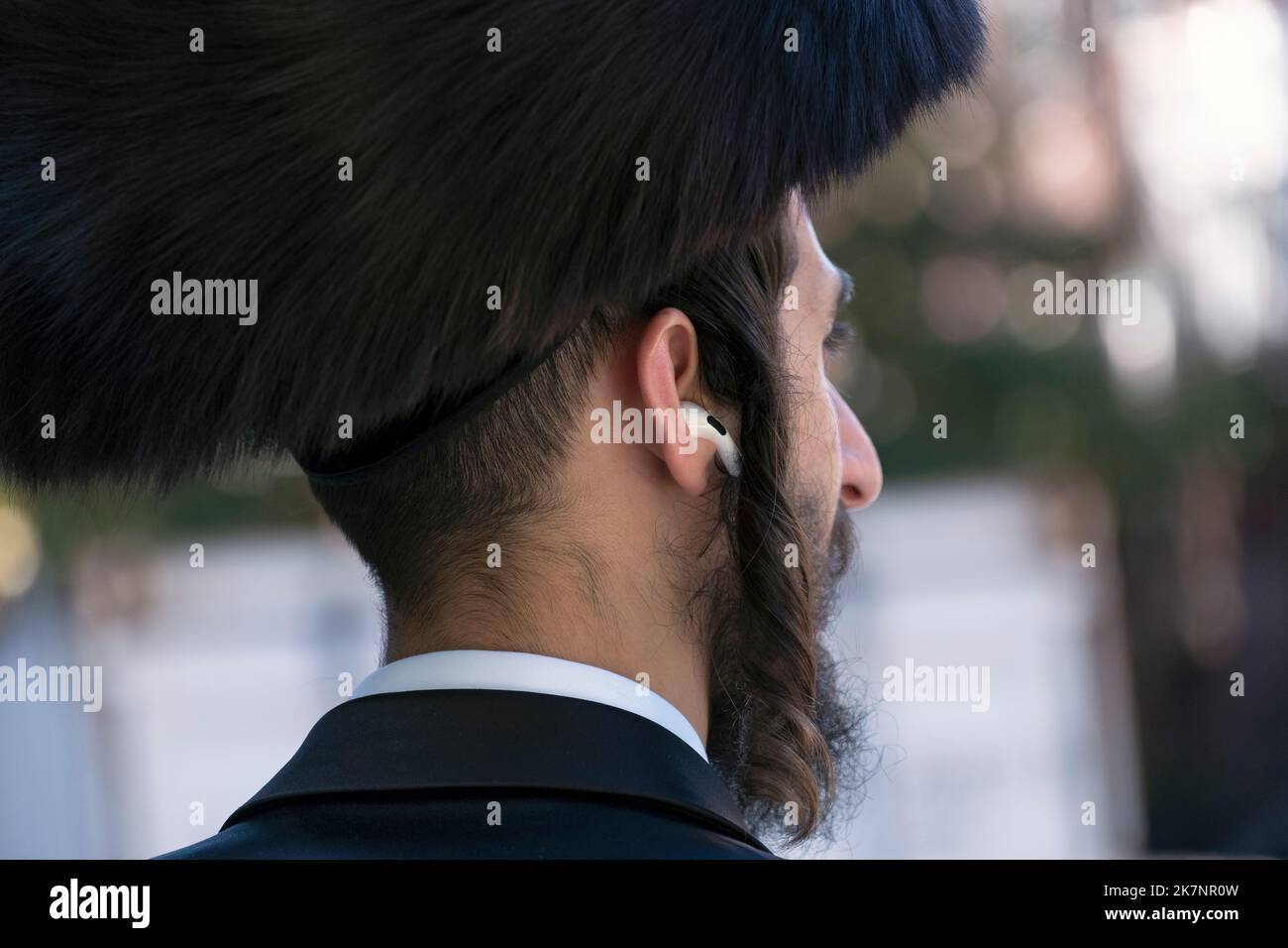 A Hasidic Jewish Man With Long Curly Peyus And A Shtreimel Fur Hat Wearing Apple Airpods In