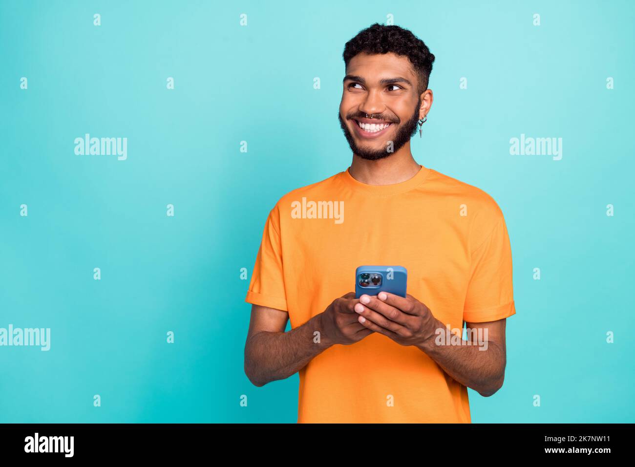 Photo of cute dreamy guy wear orange t-shirt typing facebook telegram ...