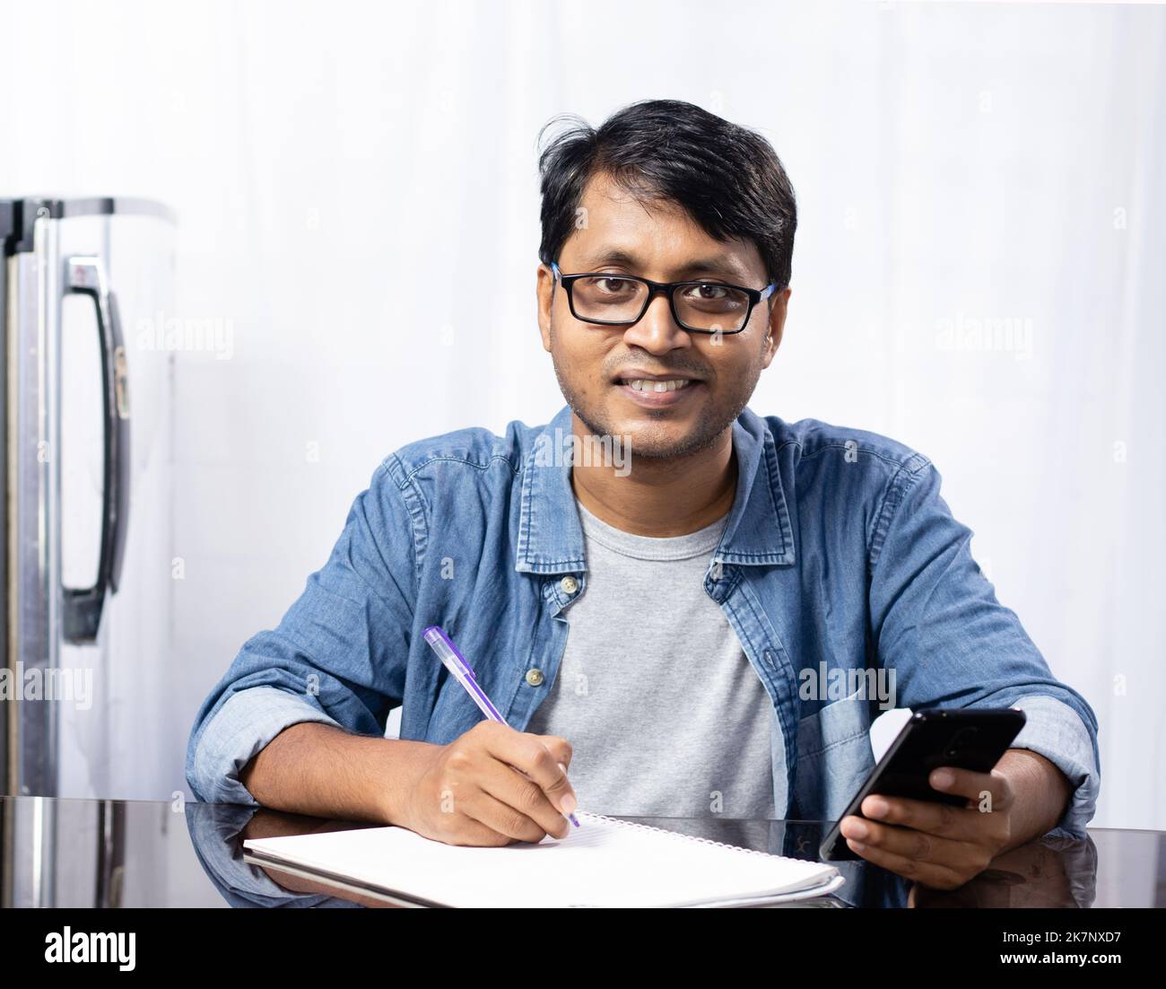 An Indian young male looking at camera with smiling face while studying ...