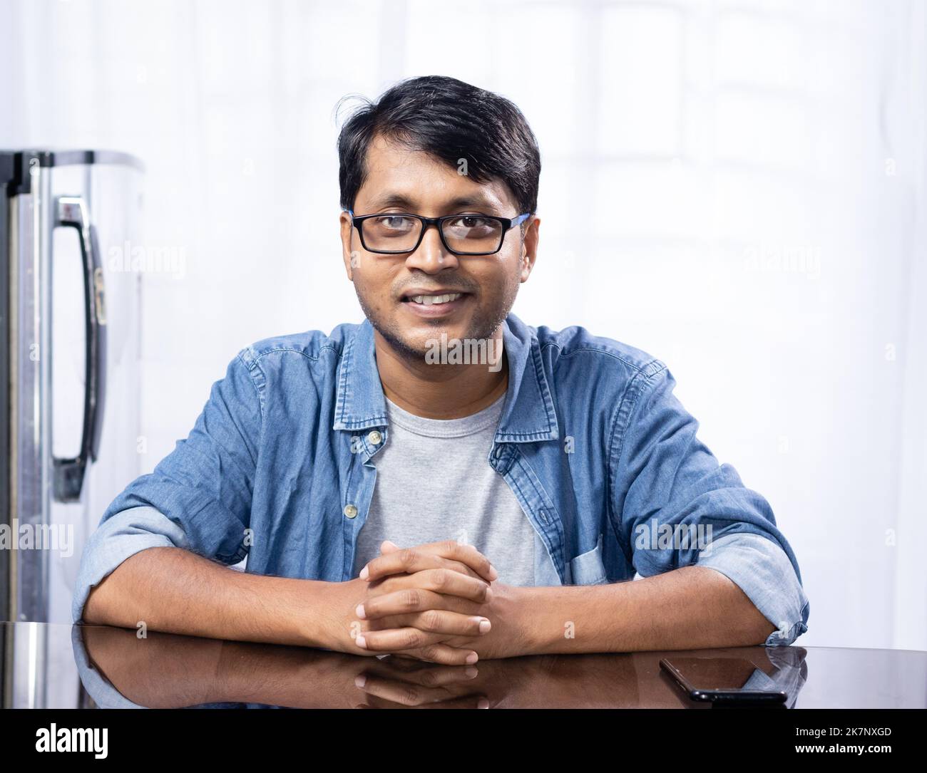 Portrait of a young middle aged Indian male wearing eyeglasses sitting ...