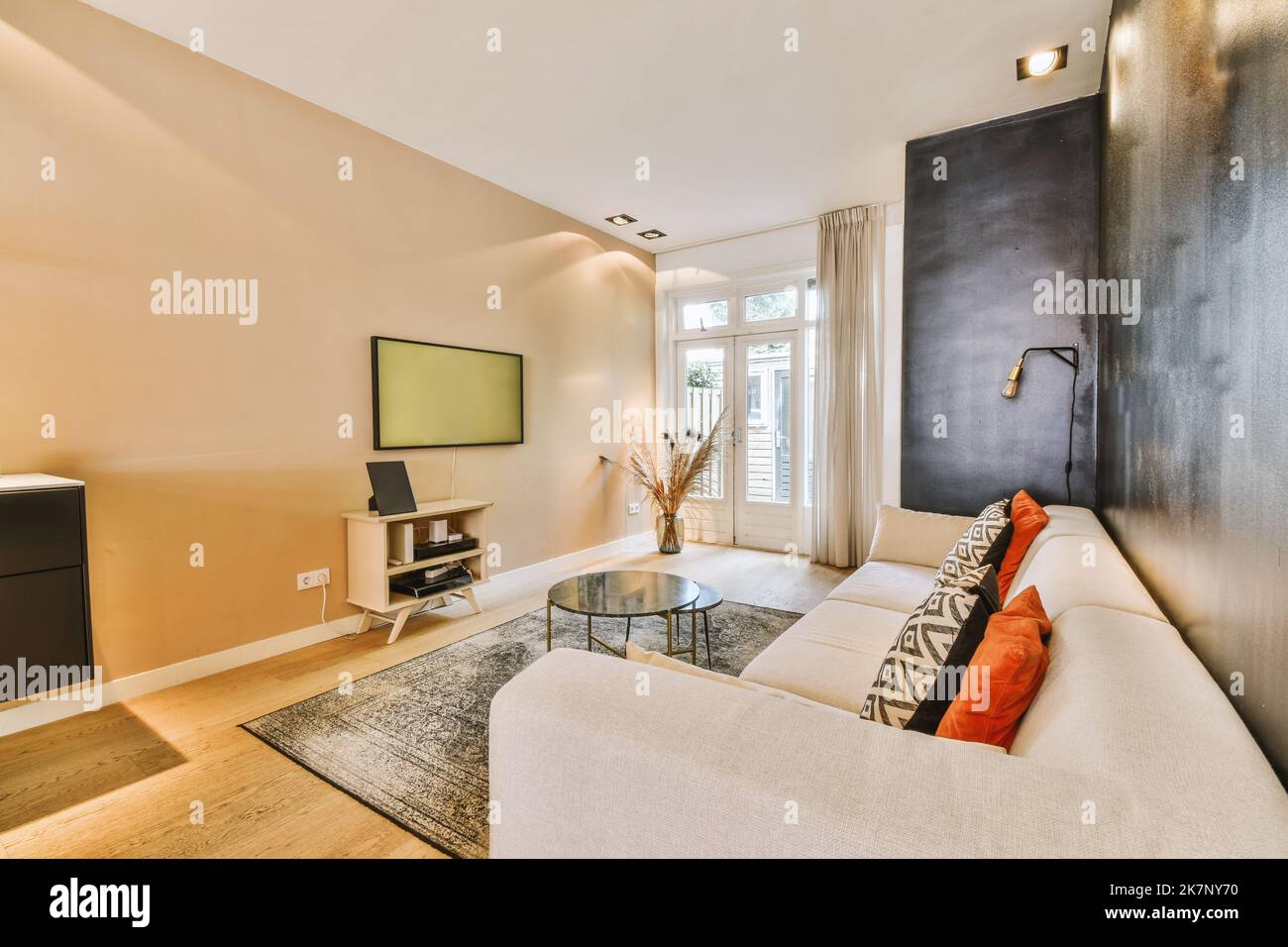 Interior of living room with comfortable sofa and TV against windows in ...