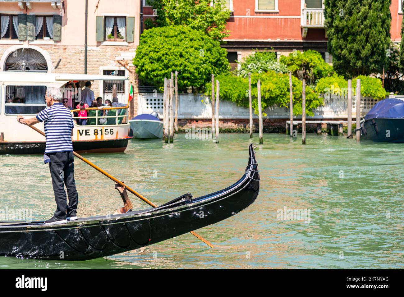 A gondolier rowing a gondola along the Grand Canal in Venice, Italy ...
