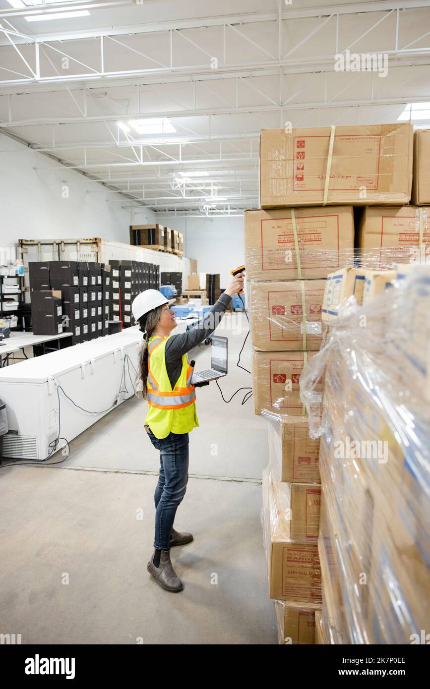 Female warehouse worker scanning cardboard boxes Stock Photo - Alamy
