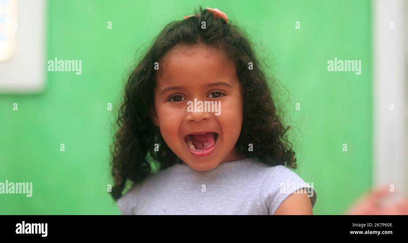Hispanic little girl waving hello to camera. South american kid waves ...