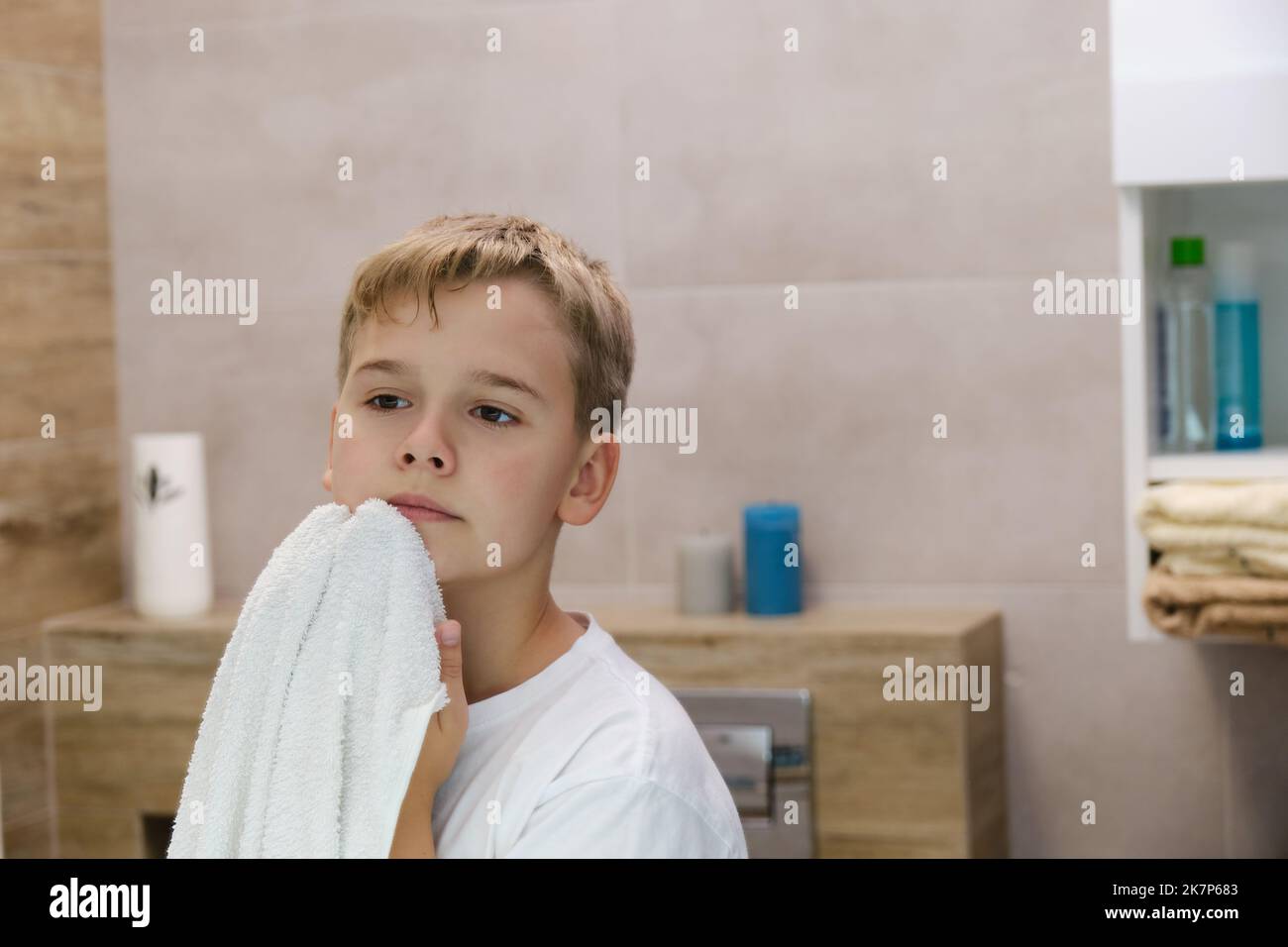 Reflection of schoolboy wiping his face with a towel after washing in ...