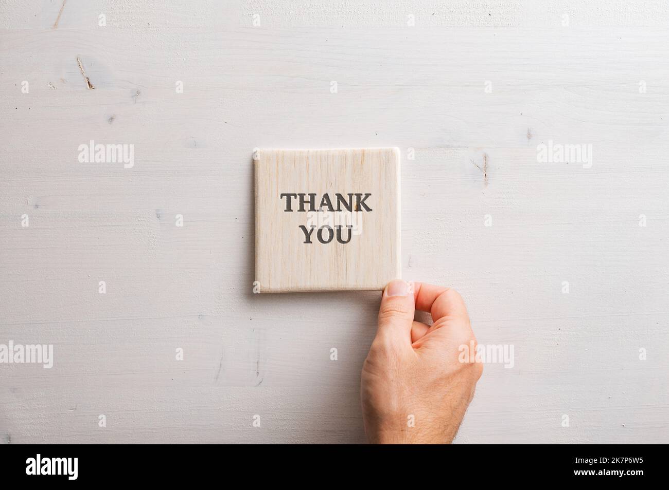 Male hand placing a wooden tile with a Thank you sign on it over a ...