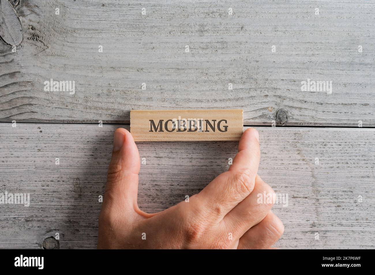 Male hand placing a wooden peg with Mobbing sign on it over white ...