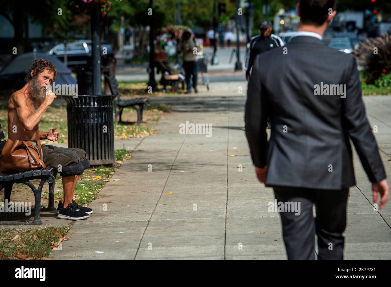During the lunch hour, people pass by a man brushing his teeth in a ...