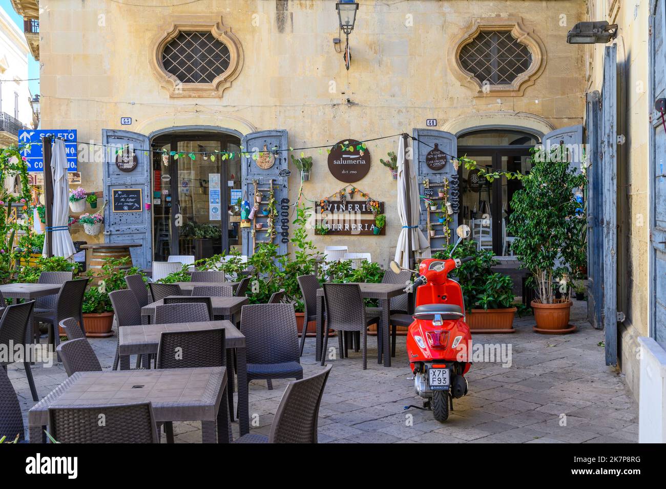 Outdoor seating and red moped in front of restaurant Salumeria Di Turno ...