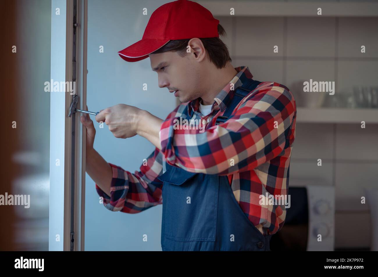 Calm focused serviceman installing the window locking mechanism Stock ...