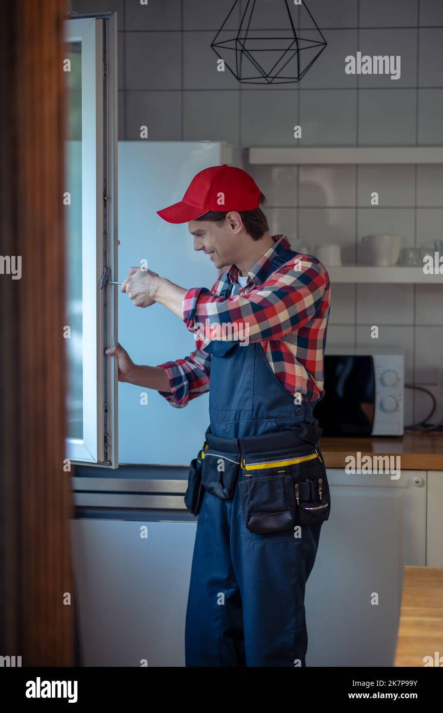 Cheerful young man mounting a kitchen window Stock Photo - Alamy