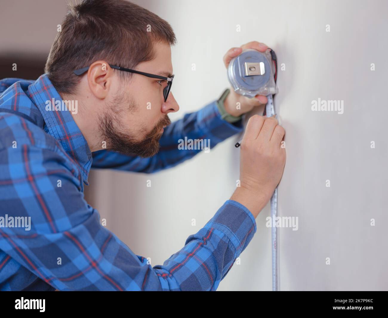 young man in blue work suit holding measure tape isolated on white ...