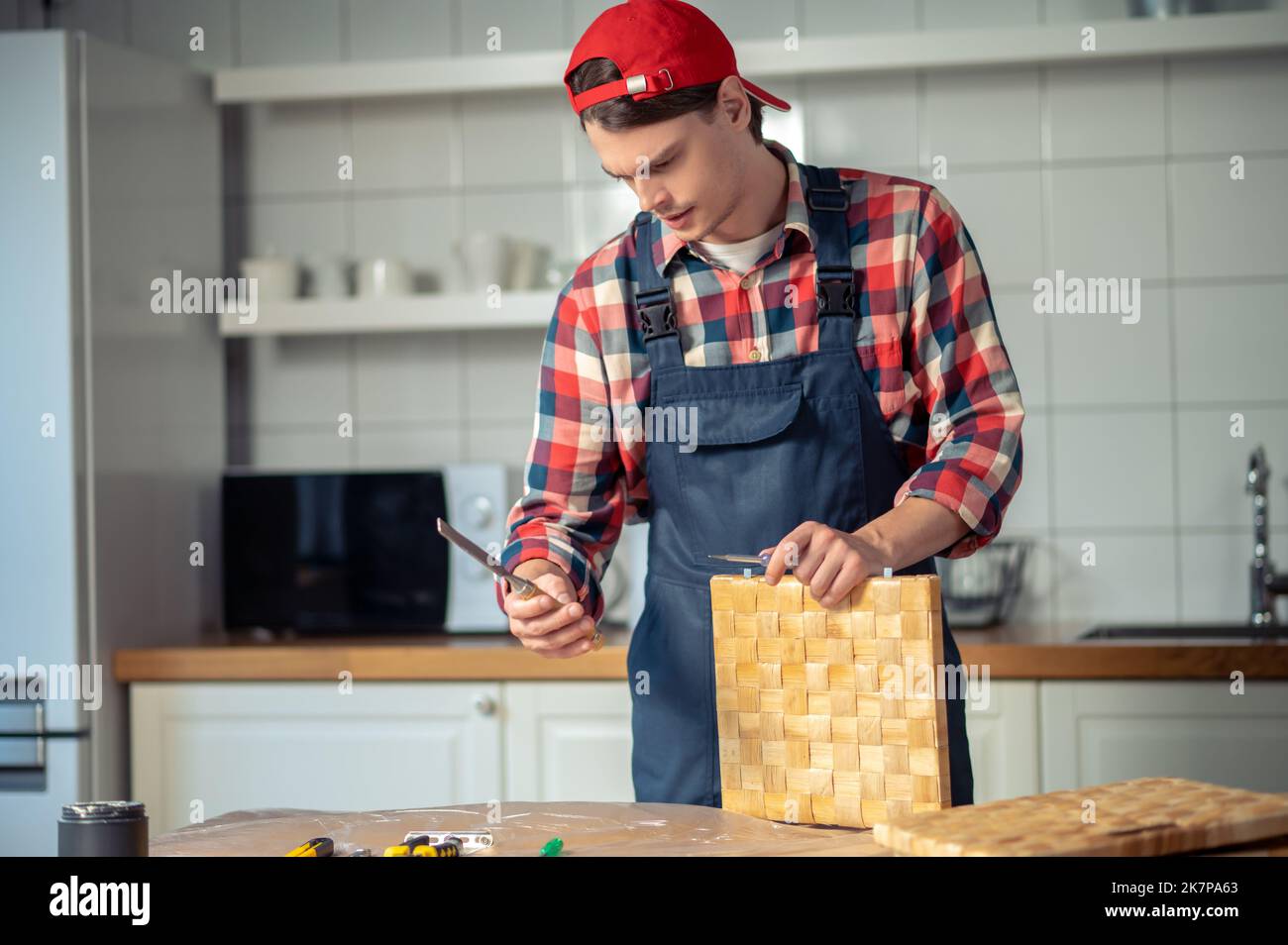 Serious focused carpenter looking at the tool in his hand Stock Photo ...