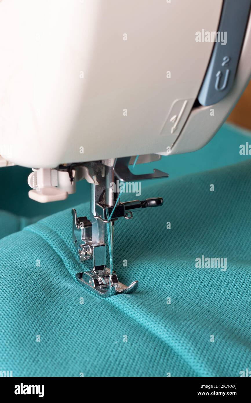 Modern sewing machine working with turquoise fabric. Sewing process ...