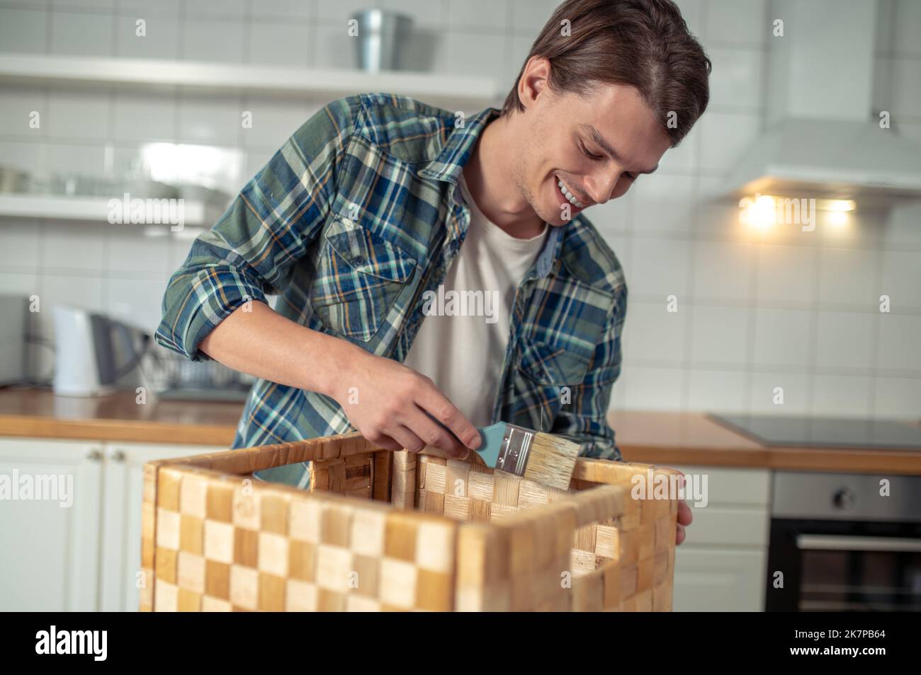 Joyful craftsman painting the inside of the straw box Stock Photo - Alamy