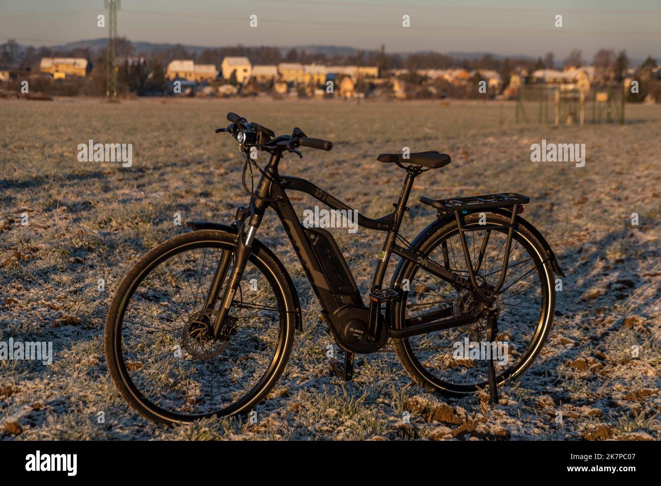 Black and gray electric bicycle in sunrise morning time on frosty field ...