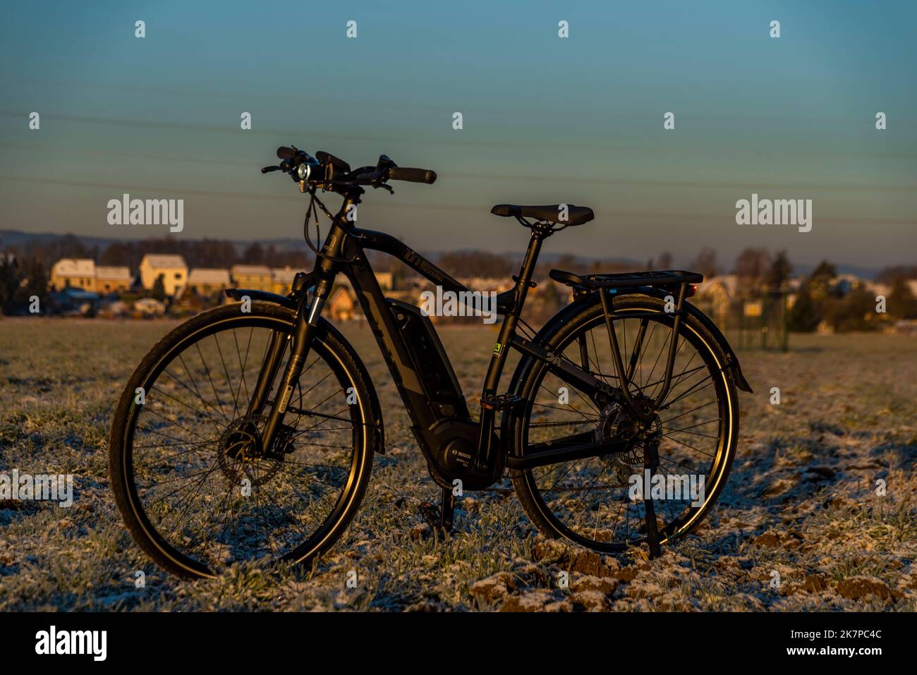 Black and gray electric bicycle in sunrise morning time on frosty field ...